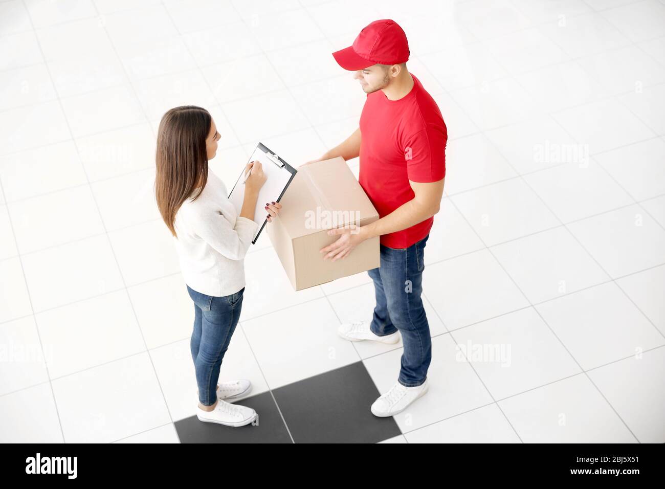 Receiving parcel - delivery man gives package to young woman Stock ...