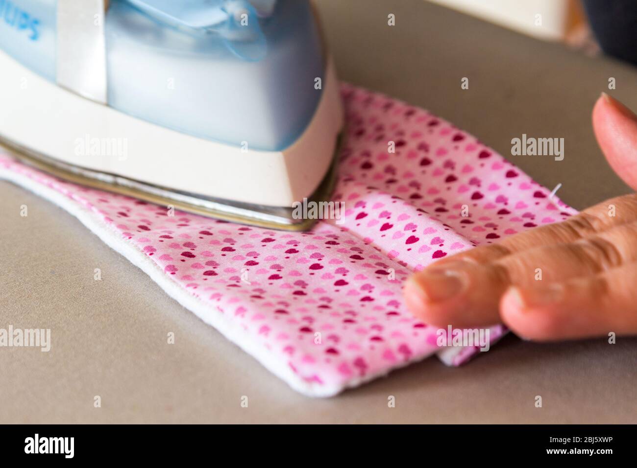 Sewing home-made face masks. Phase 4 - ironing masks Stock Photo - Alamy