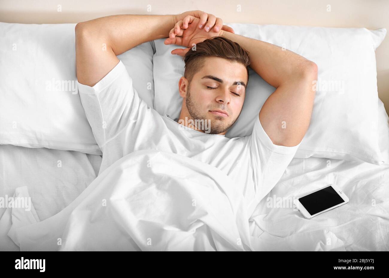 Beautiful young man snoozing on bed Stock Photo - Alamy