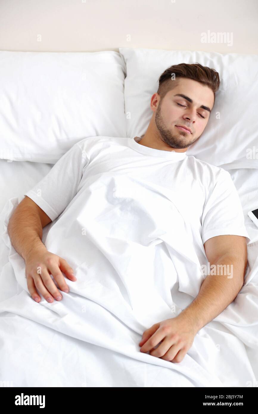 Beautiful young man snoozing on bed Stock Photo - Alamy