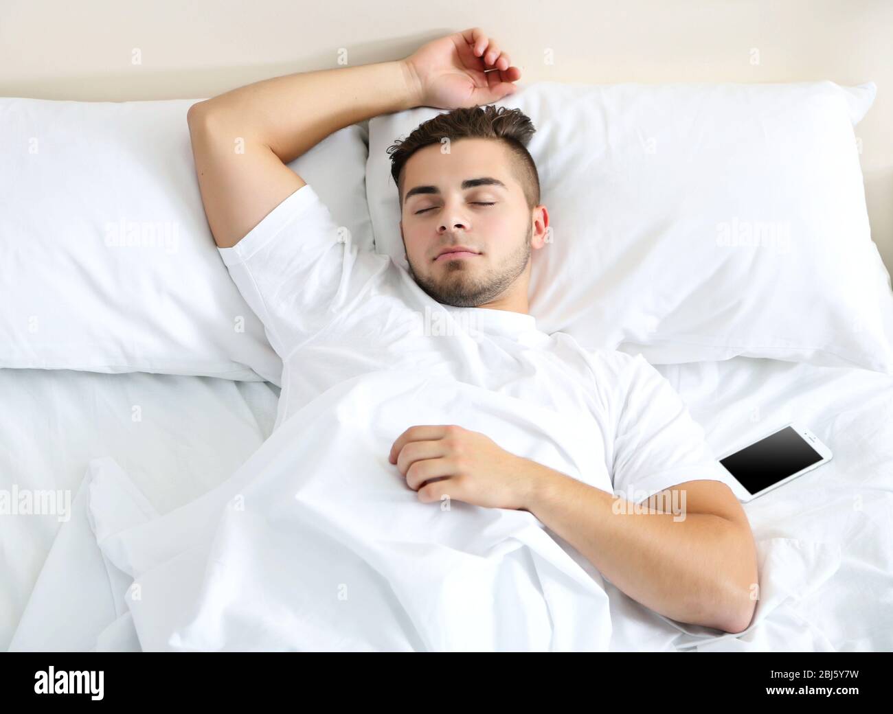 Beautiful young man snoozing on bed Stock Photo - Alamy