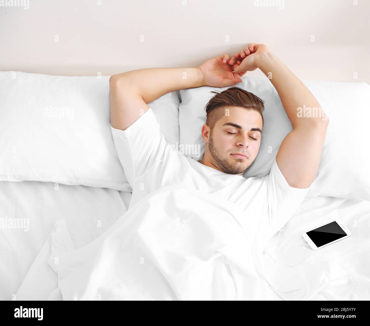 Beautiful young man snoozing on bed Stock Photo - Alamy