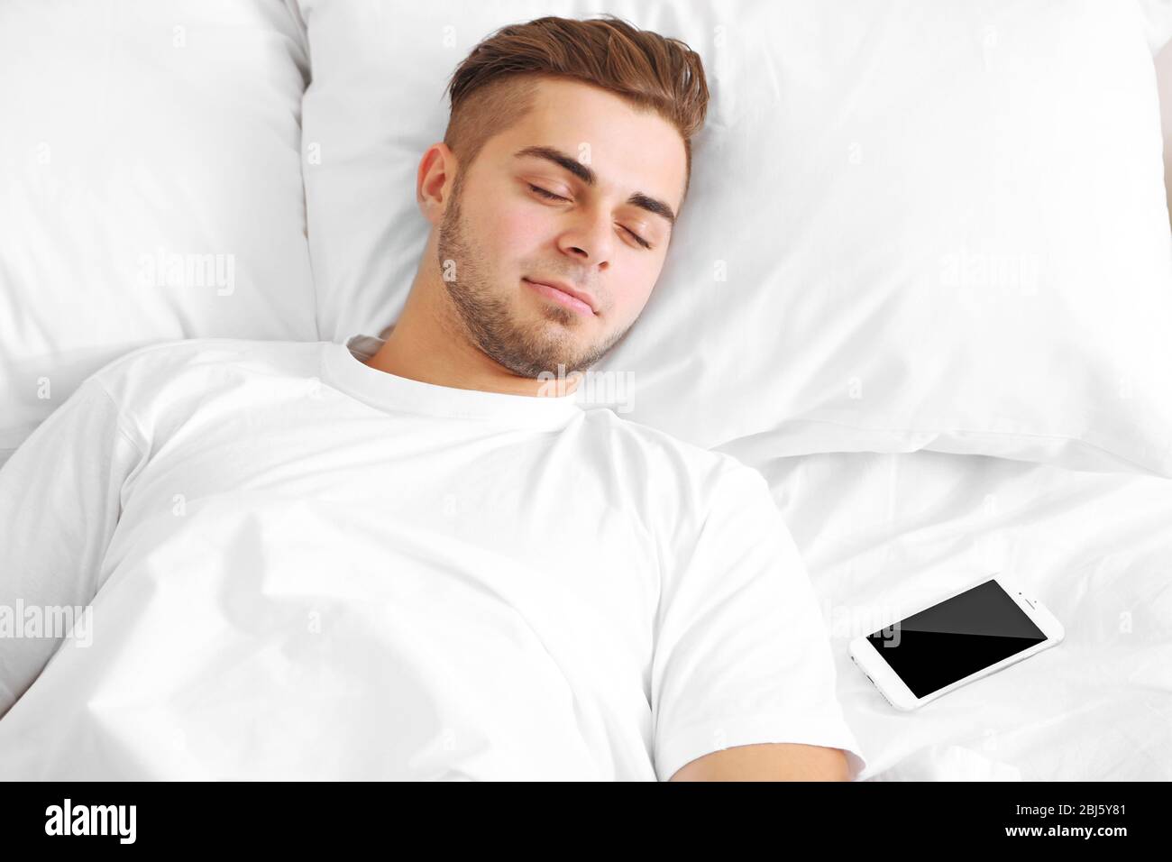 Beautiful young man snoozing on bed Stock Photo - Alamy