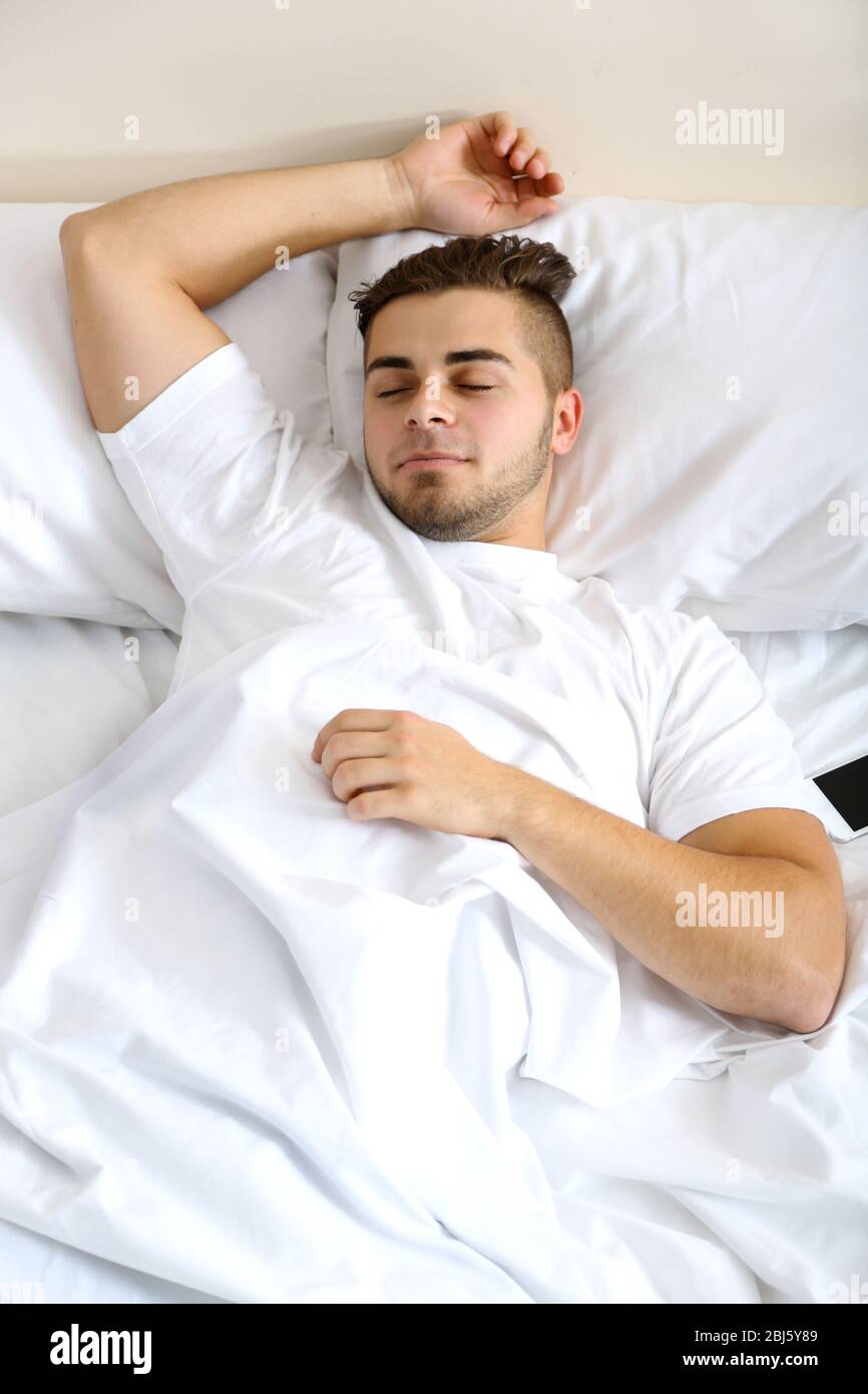 Beautiful young man snoozing on bed Stock Photo - Alamy