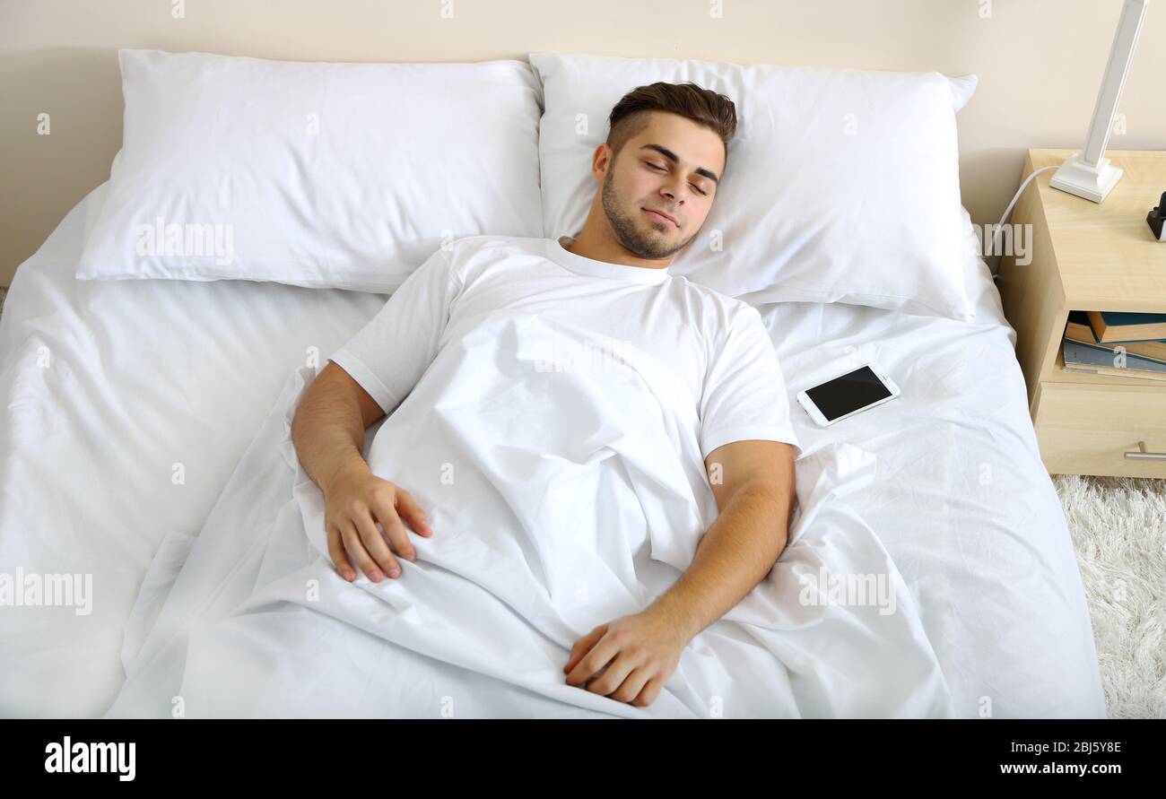 Beautiful young man snoozing on bed Stock Photo - Alamy