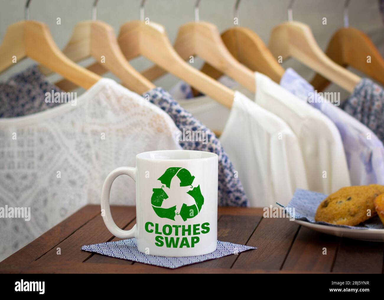 Clothes swap icon and text on mug in front of clothes at swap party ...