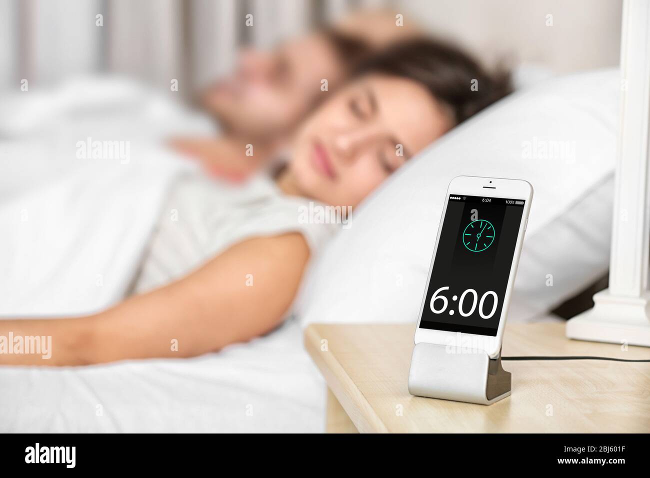 Happy couple waking up with mobile alarm clock Stock Photo - Alamy