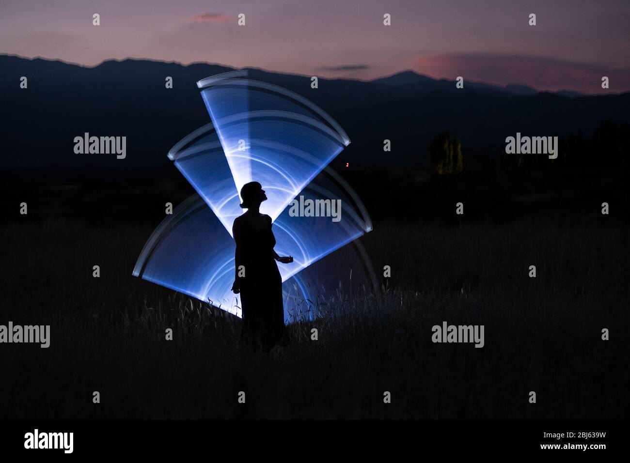 silhouette of woman through blue light lightpainting at sunset in the ...