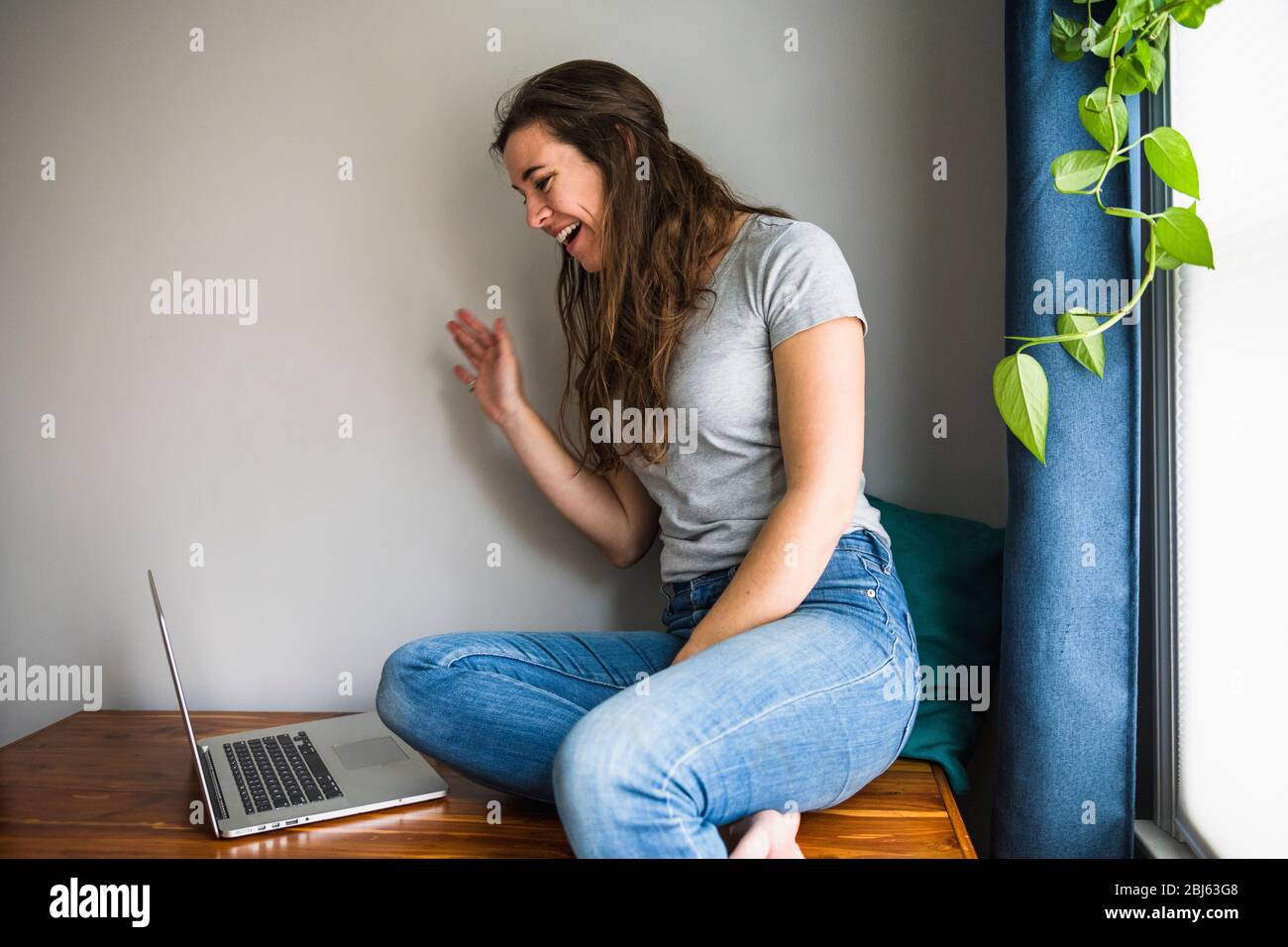Smiling portrait of Individual Woman Facetiming on laptop from home ...