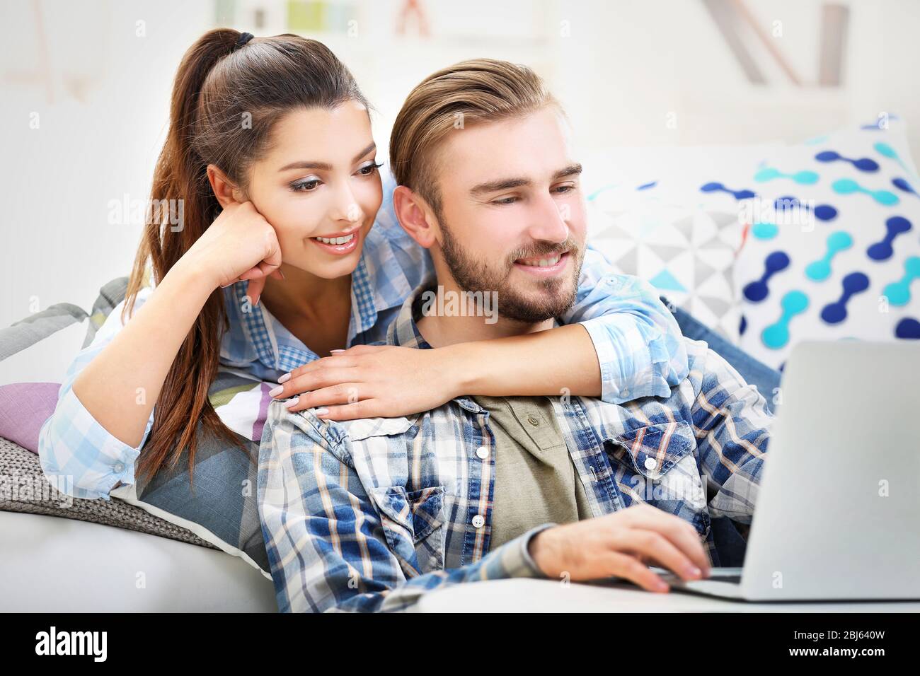 Happy couple sitting at the table and working with a laptop Stock Photo ...