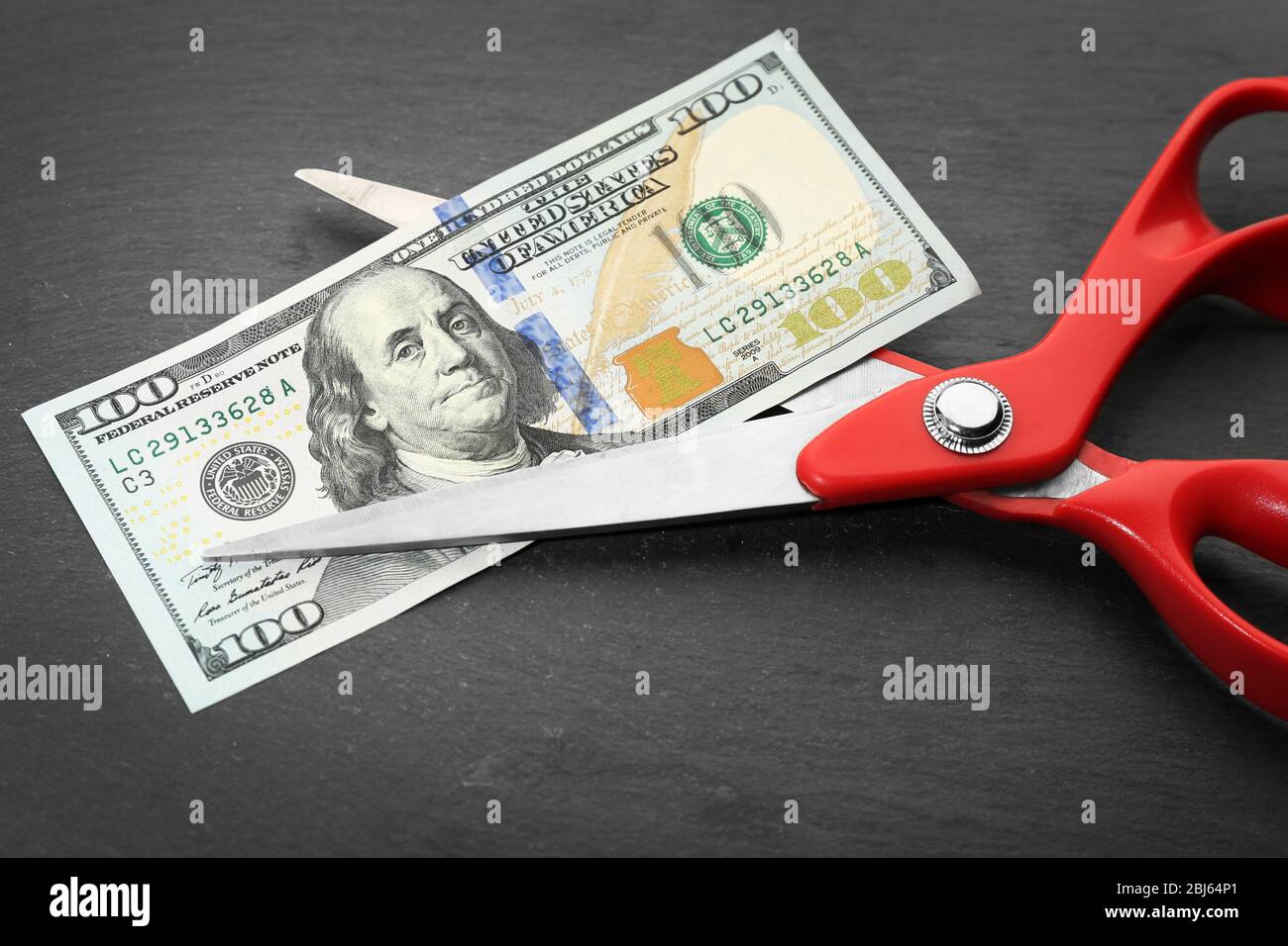 Red scissors cut money on black background. Financial concept Stock ...