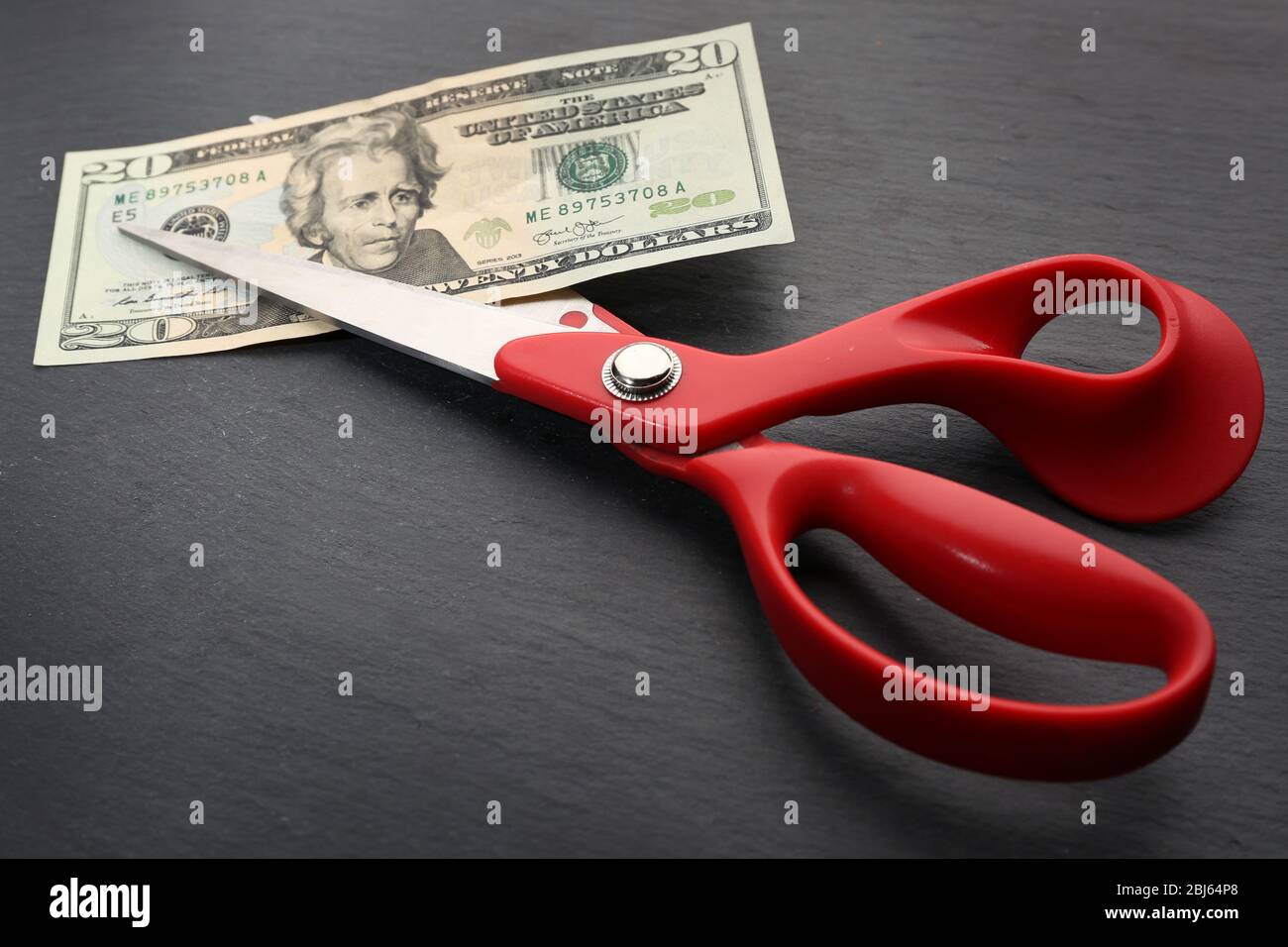 Red scissors cut money on black background. Financial concept Stock ...