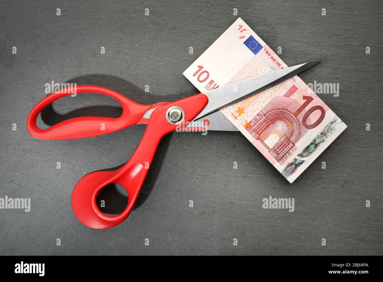 Red scissors cut money on black background. Financial concept Stock ...