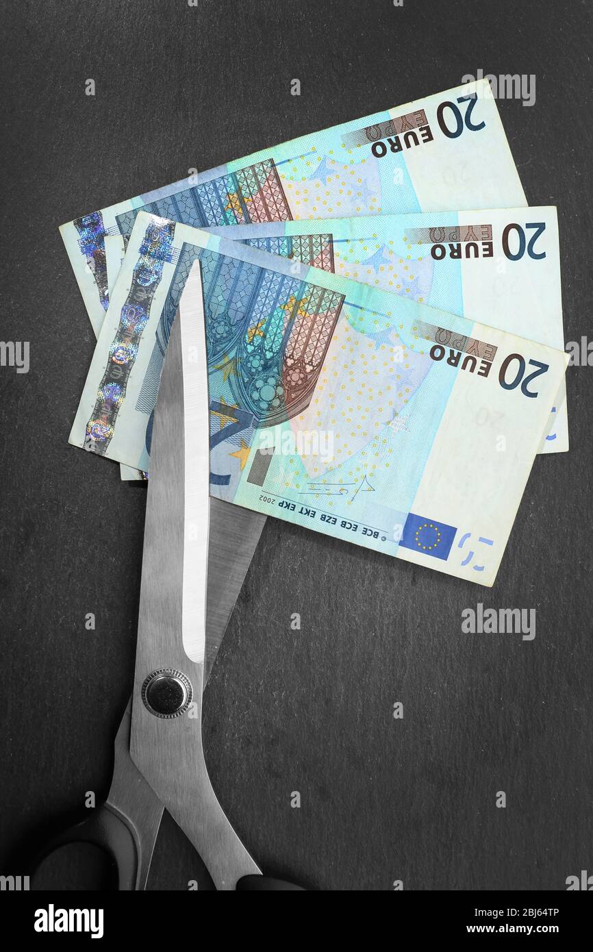 Concept of spending money - scissors cut money on black background ...