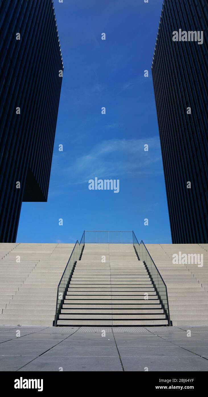 Modern Stair with a handrail in the middle going up to the blue sky ...