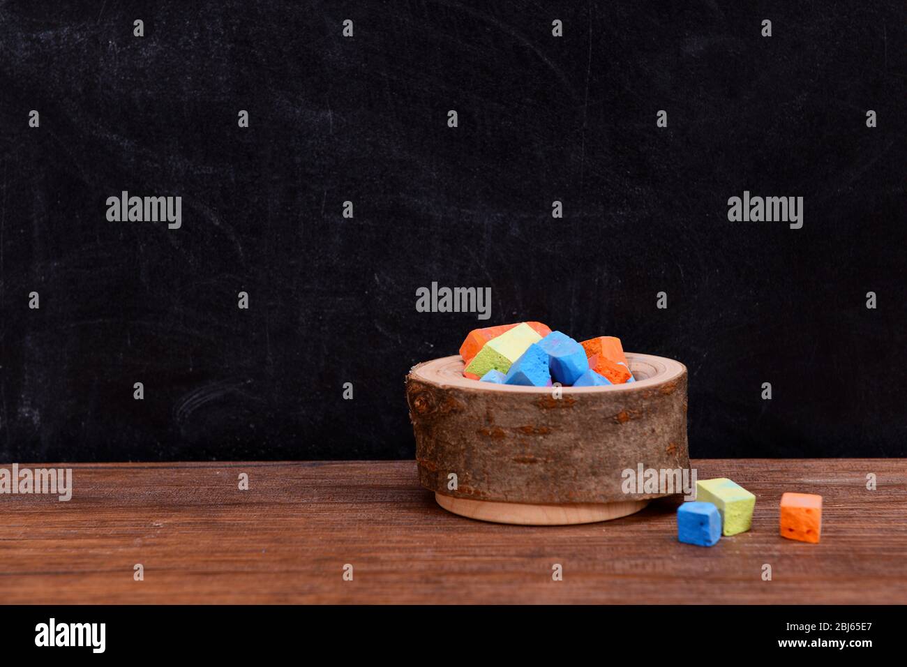 Wooden bowl of coloured chalk on desk in front of blackboard Stock ...