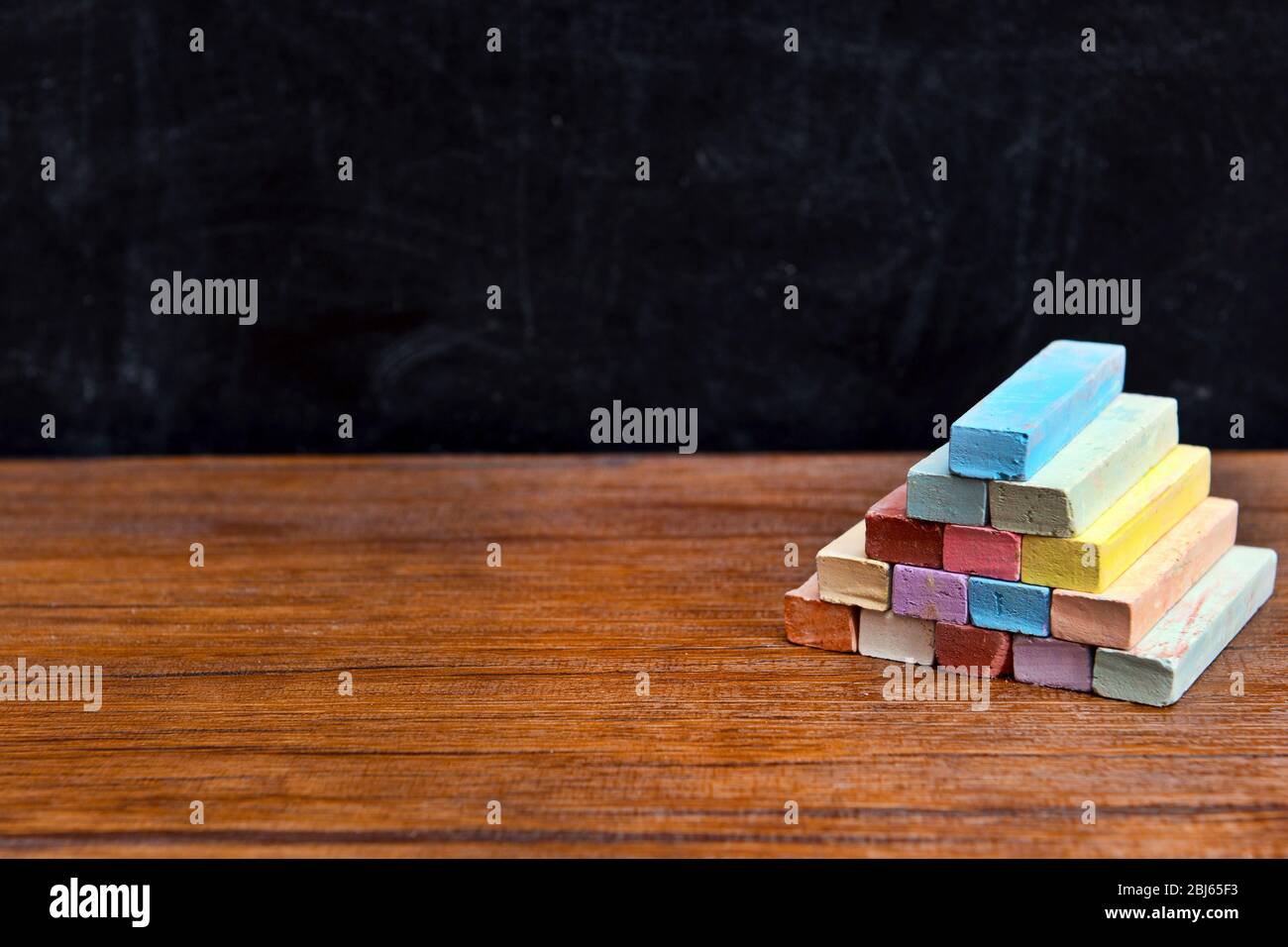 Coloured chalk on desk in front of blackboard Stock Photo - Alamy