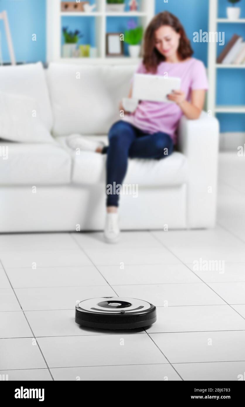 Cleaning concept - automatic robotic hoover clean the room while woman ...