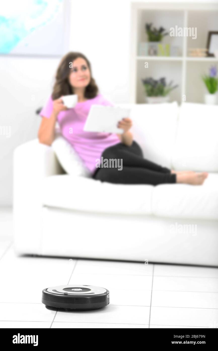 Cleaning concept - automatic robotic hoover clean the room while woman ...