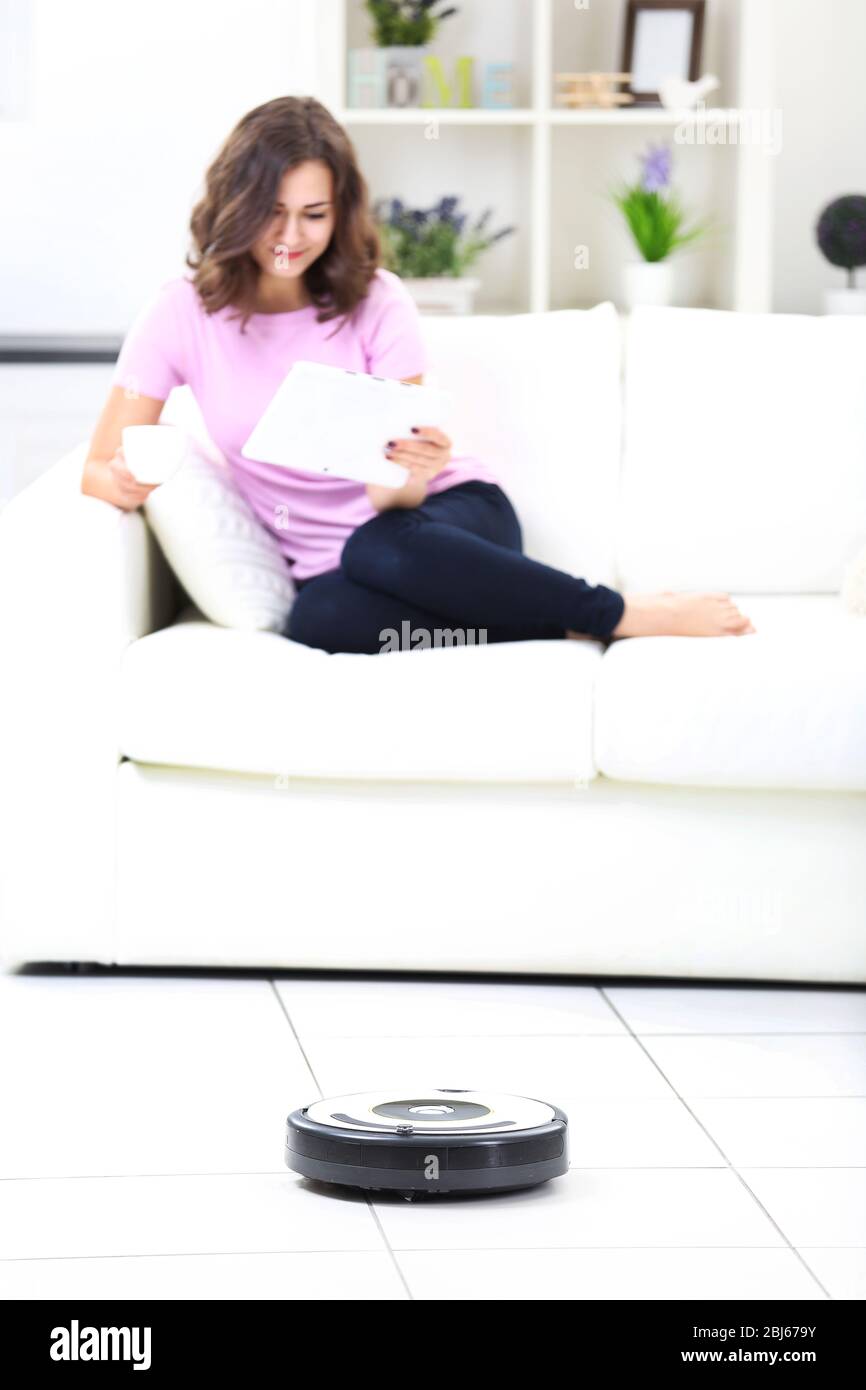Cleaning concept - automatic robotic hoover clean the room while woman ...
