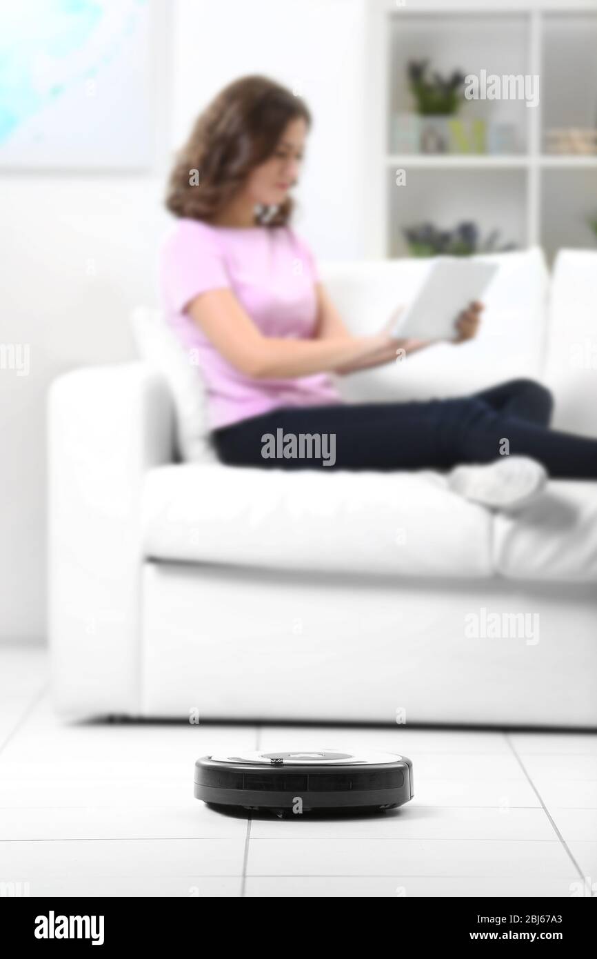 Cleaning concept - automatic robotic hoover clean the room while woman ...