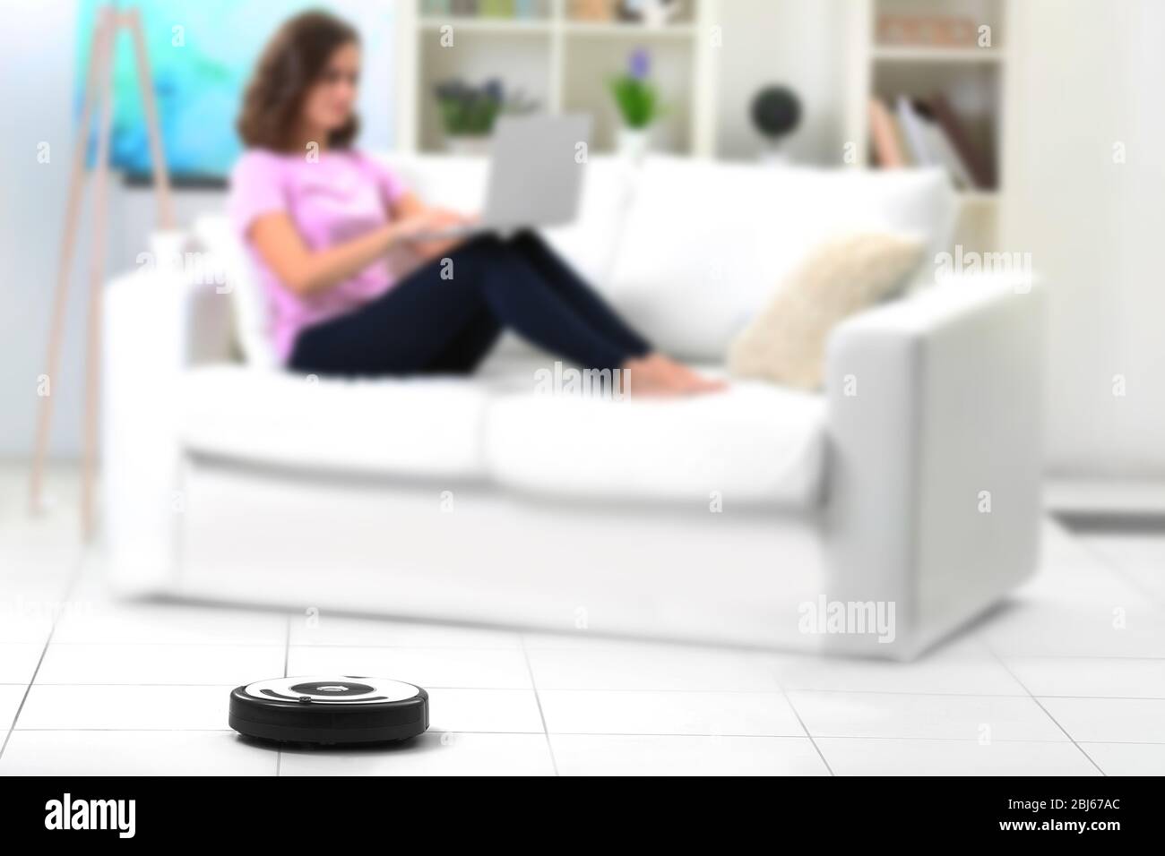 Cleaning concept - automatic robotic hoover clean the room while woman ...