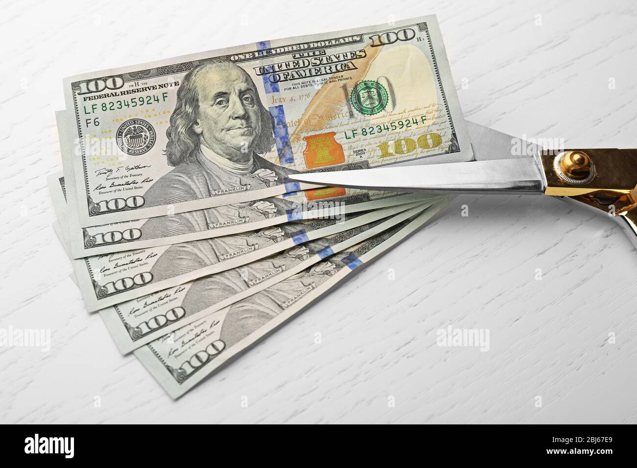 Scissors cuts dollar banknote on table Stock Photo - Alamy