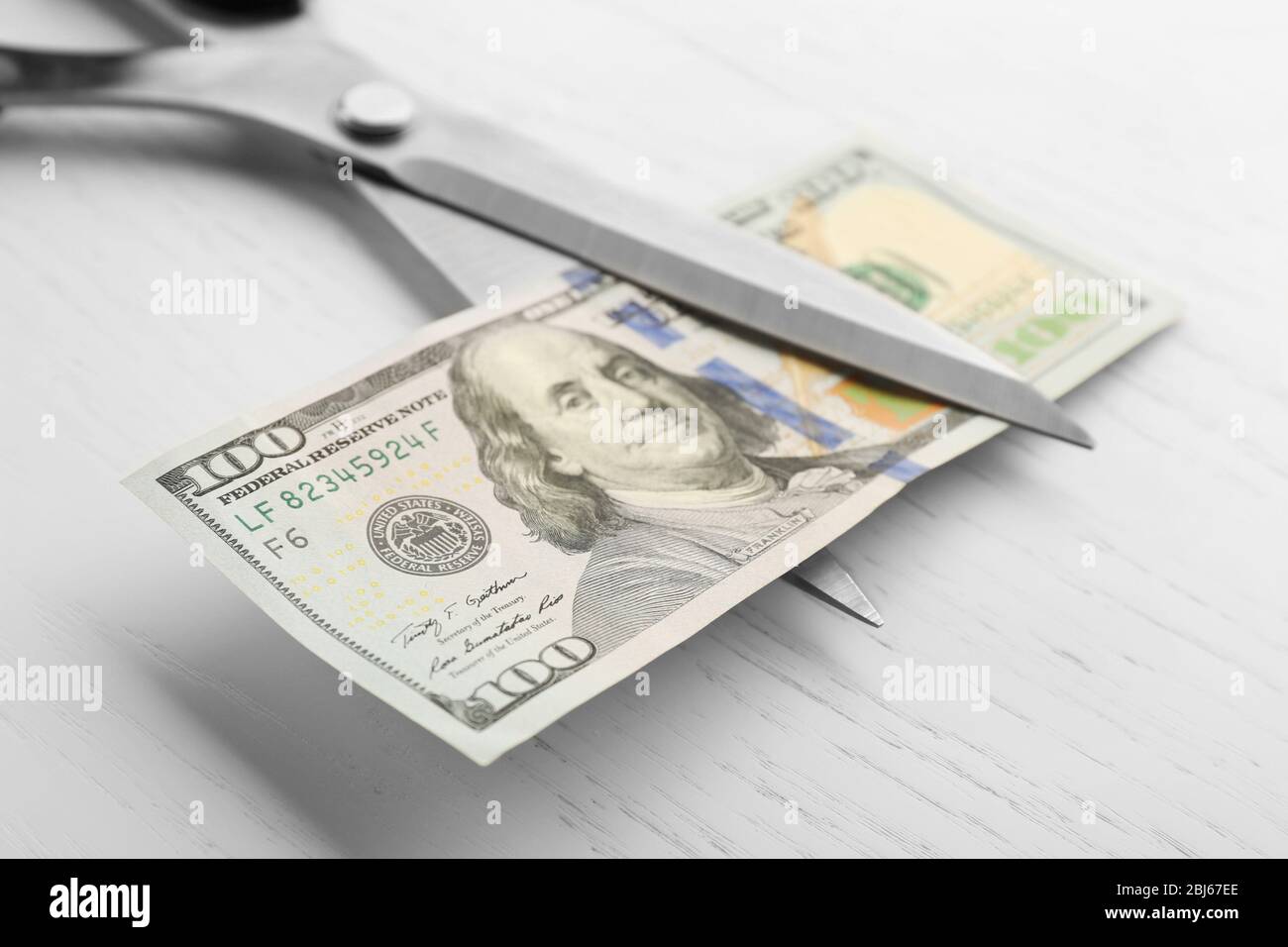 Scissors cuts dollar banknote on table Stock Photo - Alamy