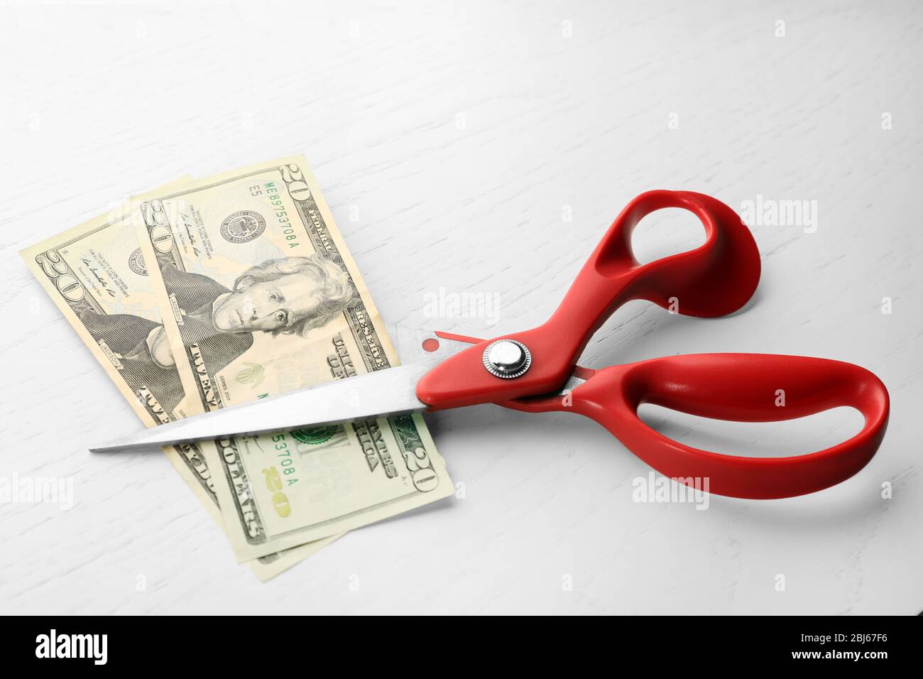 Scissors cuts dollar banknote on table Stock Photo - Alamy