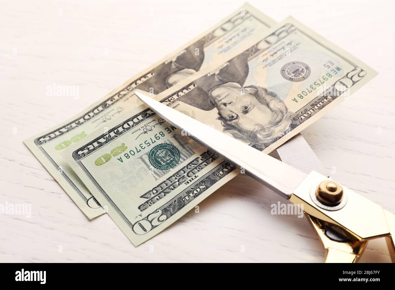 Scissors cuts dollar banknote on table Stock Photo - Alamy
