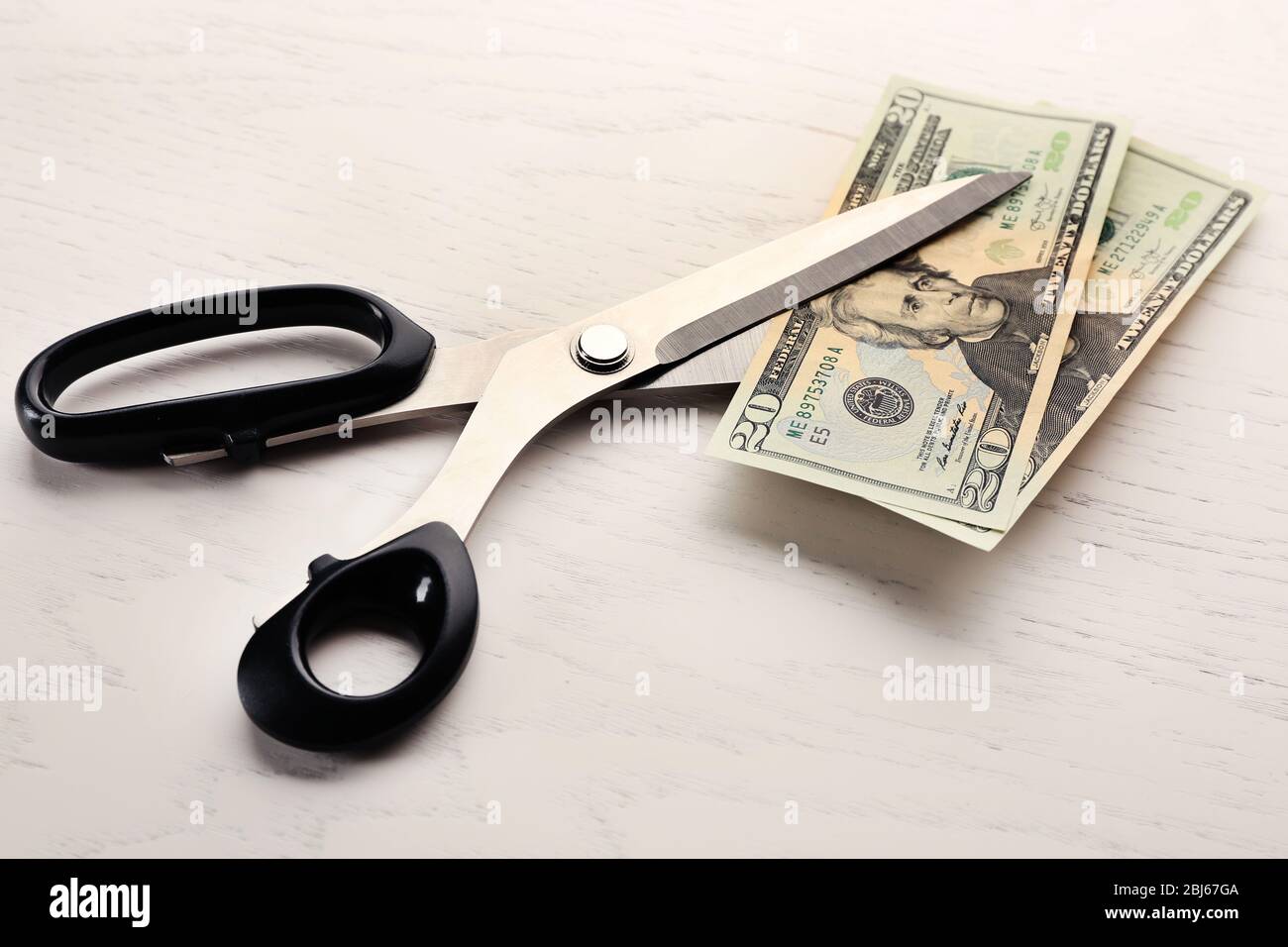 Scissors cuts dollar banknote on table Stock Photo - Alamy