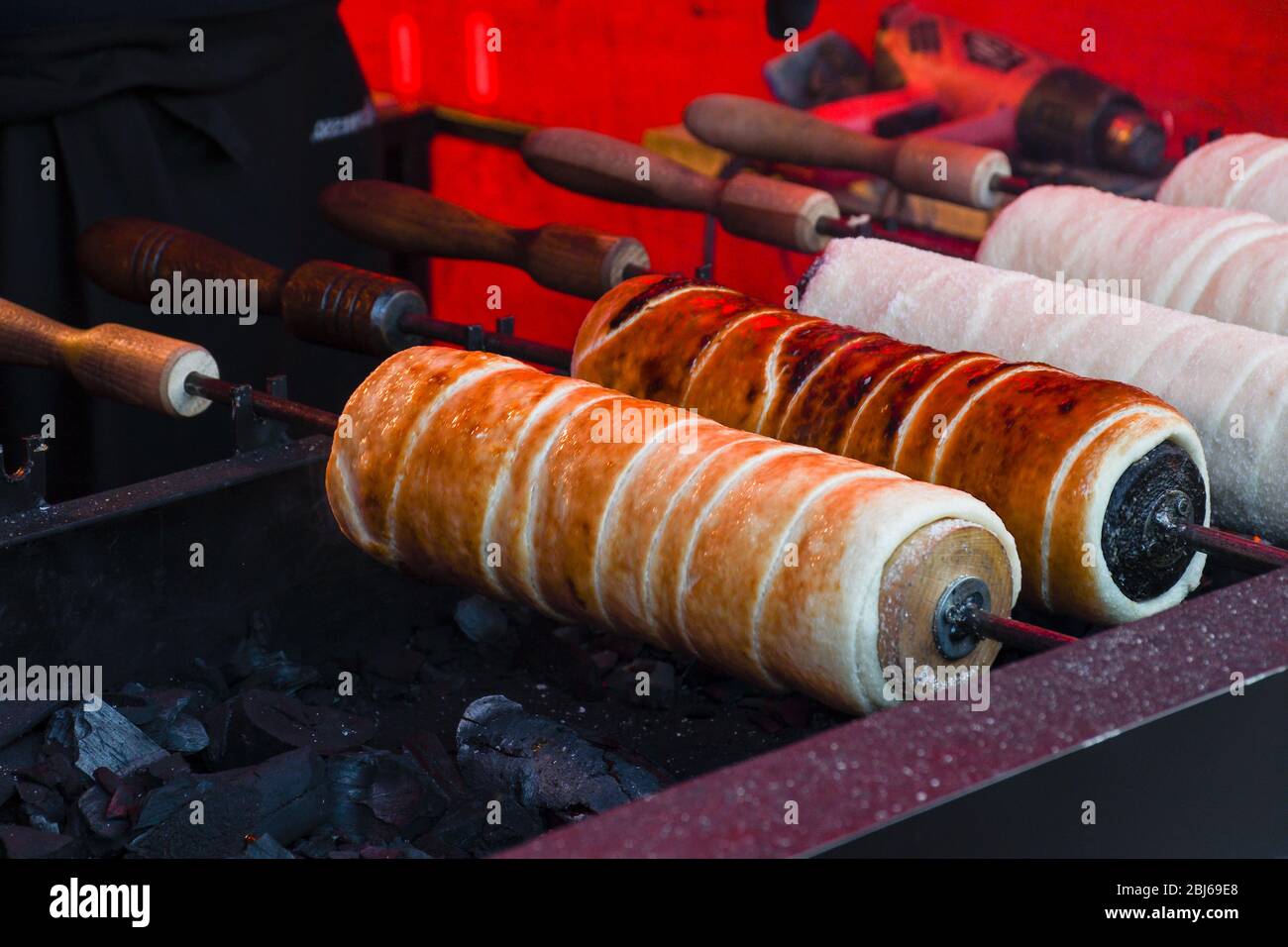 Kurtos kalacs or chimney cakes, preparing cooking on charcoal grill ...