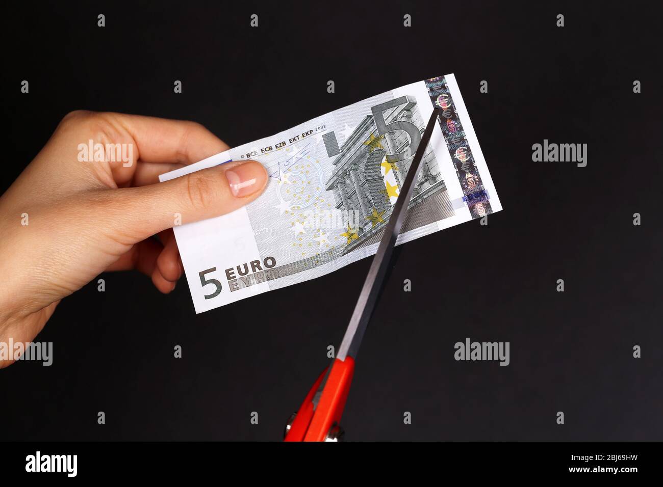 Hands with scissors cutting Euro banknote, on black background Stock ...