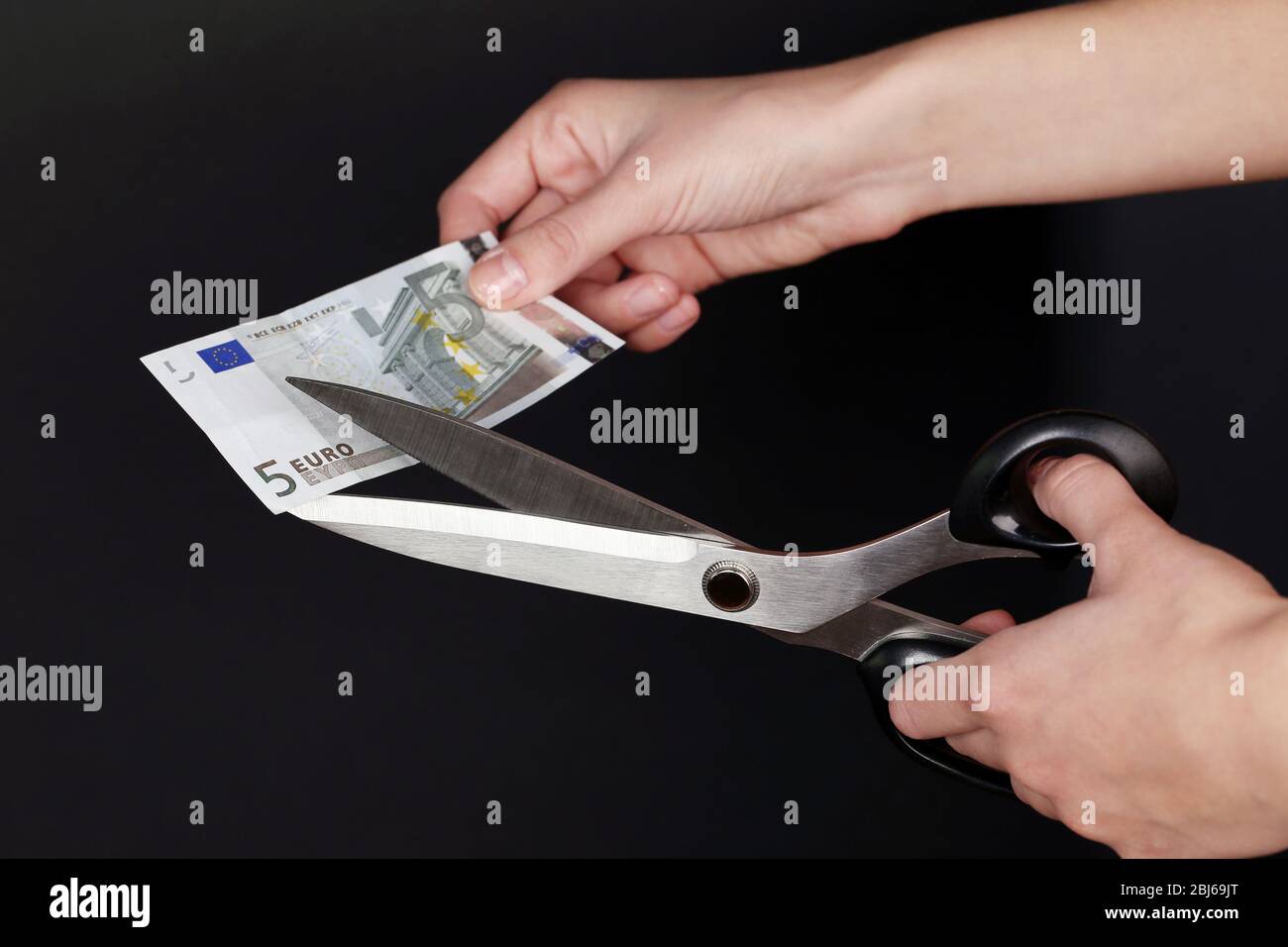 Hands with scissors cutting Euro banknote, on black background Stock ...