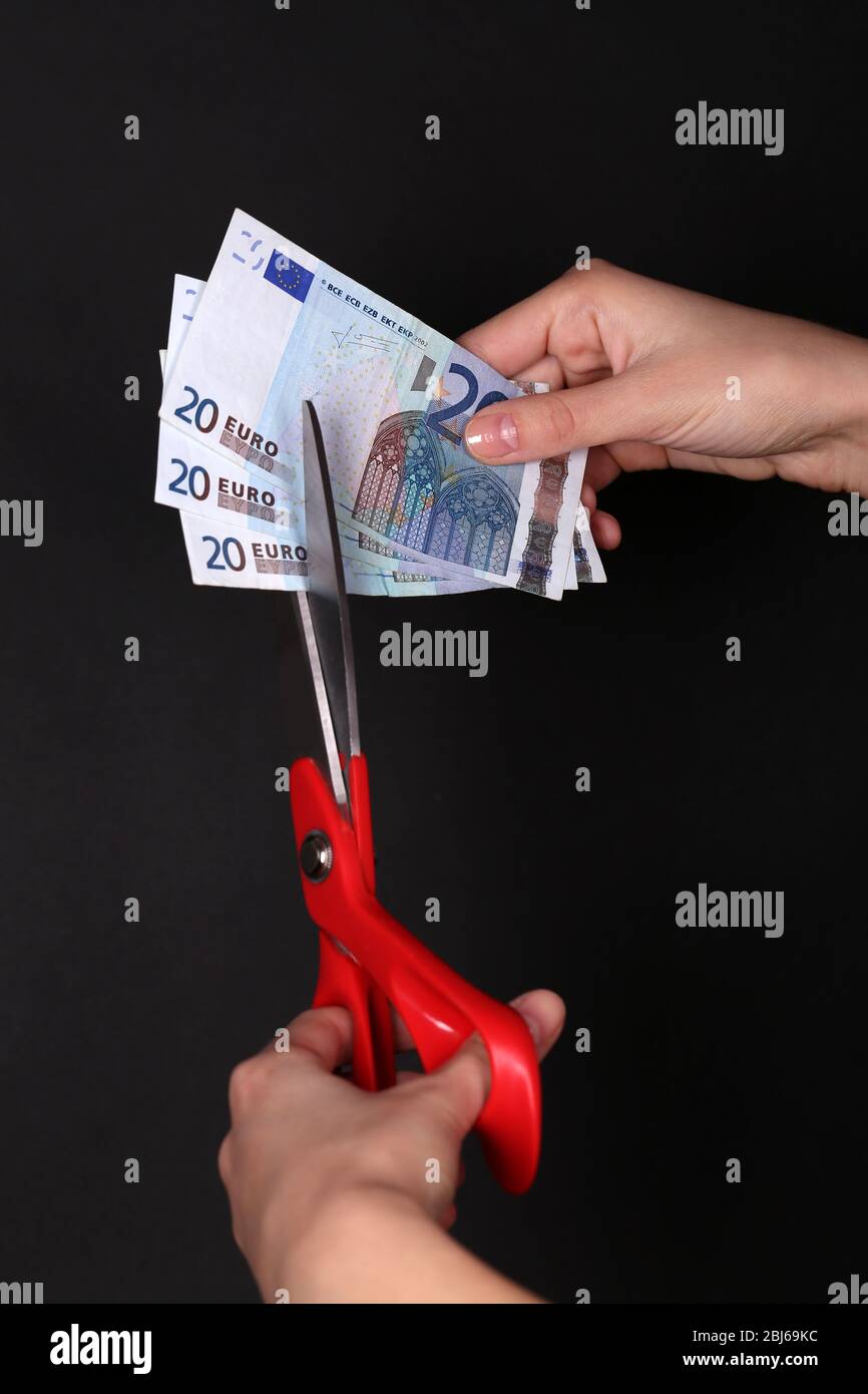 Hands with scissors cutting Euro banknotes, on black background Stock ...