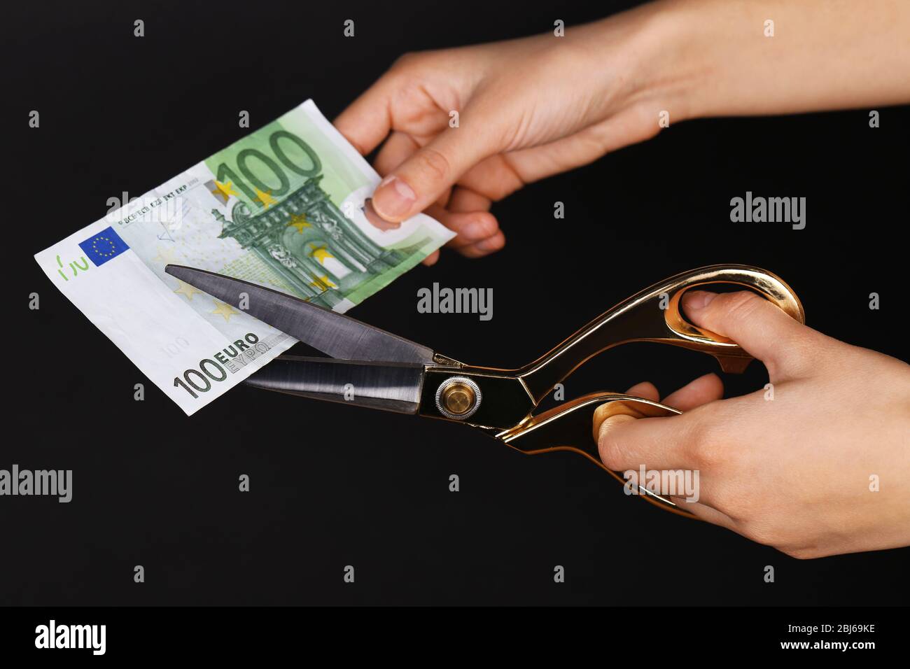 Hands with scissors cutting Euro banknote, on black background Stock ...