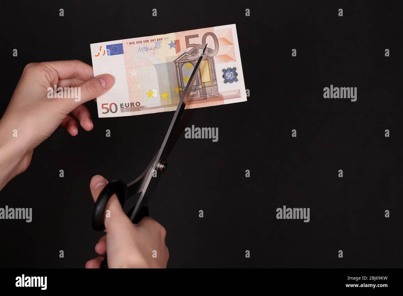 Hands with scissors cutting Euro banknote, on black background Stock ...