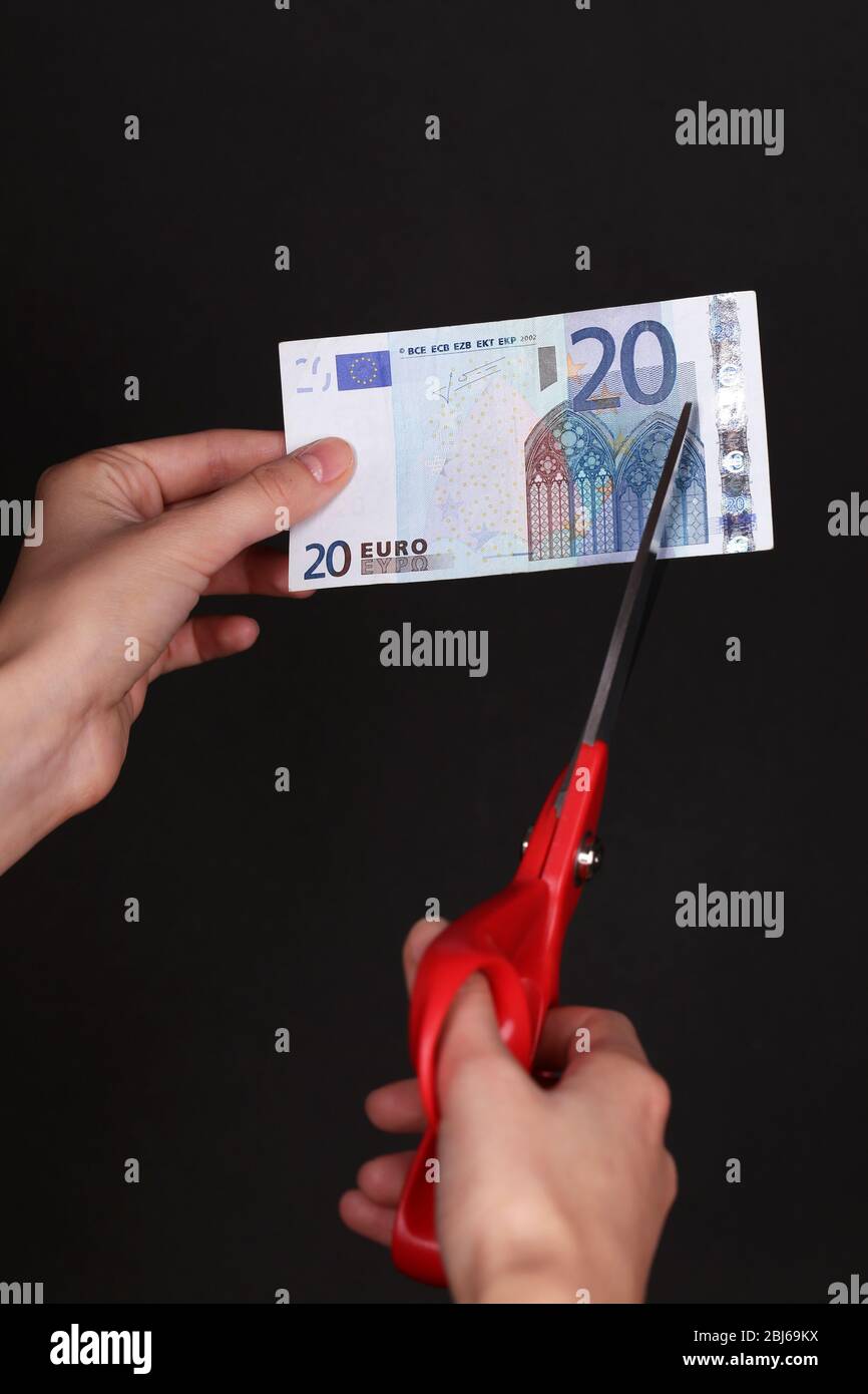 Hands with scissors cutting Euro banknote, on black background Stock ...