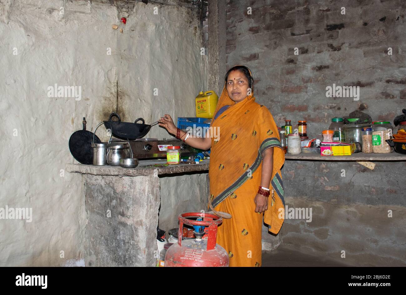 Happy rural woman standing in kitchen cooking food on gas stove Stock ...