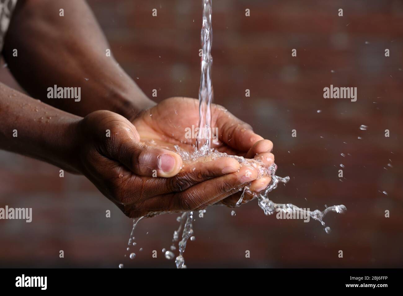 Hands washing concept. Water pouring into man hands on brick wall ...