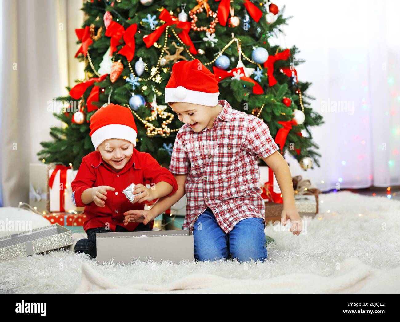 Two cute small brothers opening gifts on Christmas decoration ...