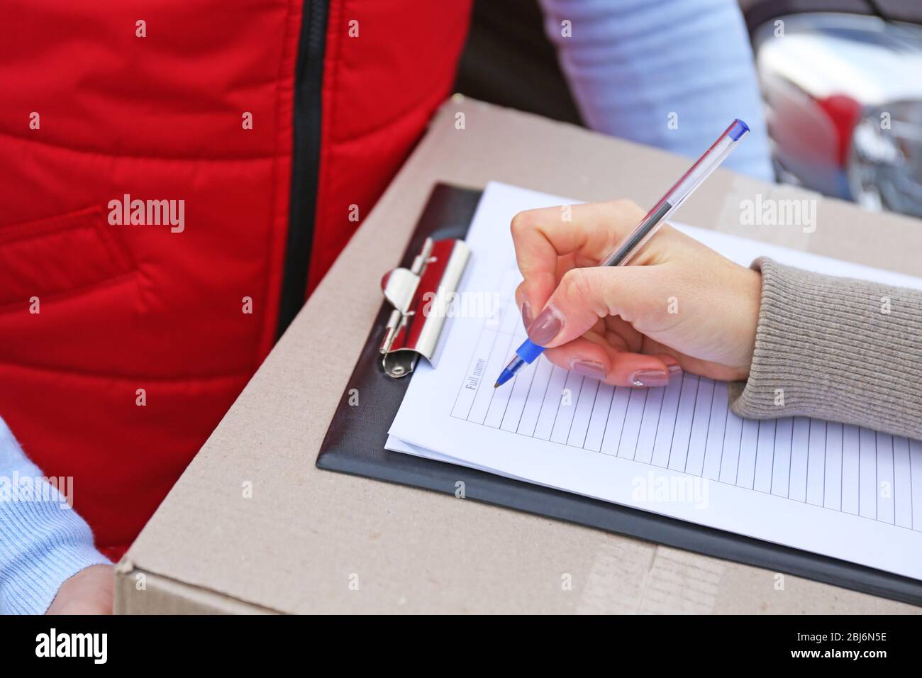 Female hand signing delivery form on the box, close-up Stock Photo - Alamy
