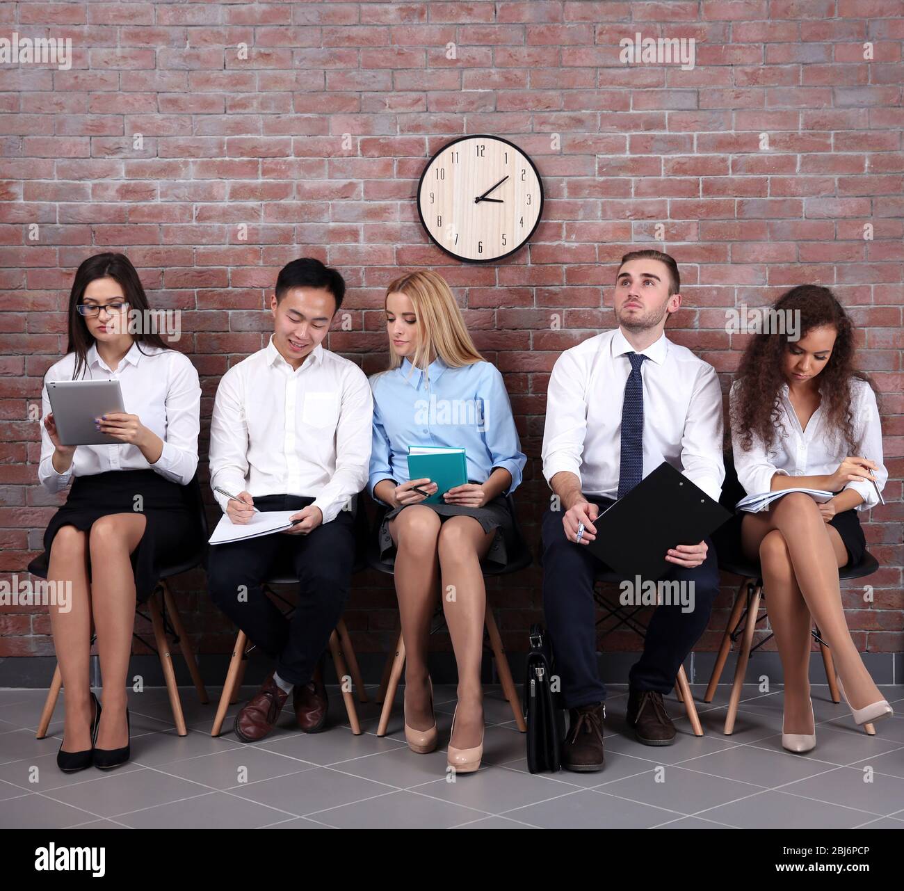 Young people sitting on a chairs in brick wall hall Stock Photo - Alamy