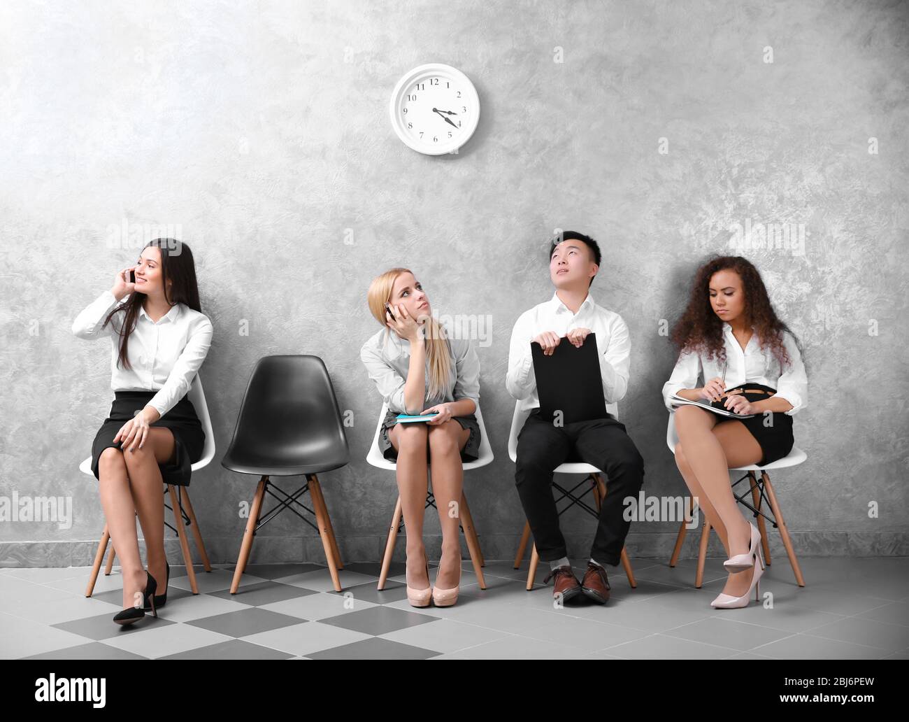 Young people sitting on a chairs in grey hall Stock Photo - Alamy