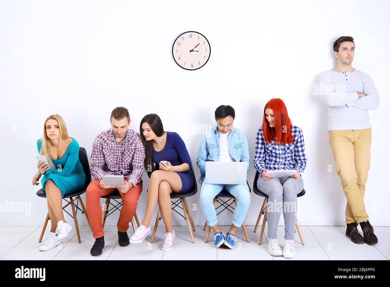 Young people sitting on a chairs and using devices in white hall Stock ...