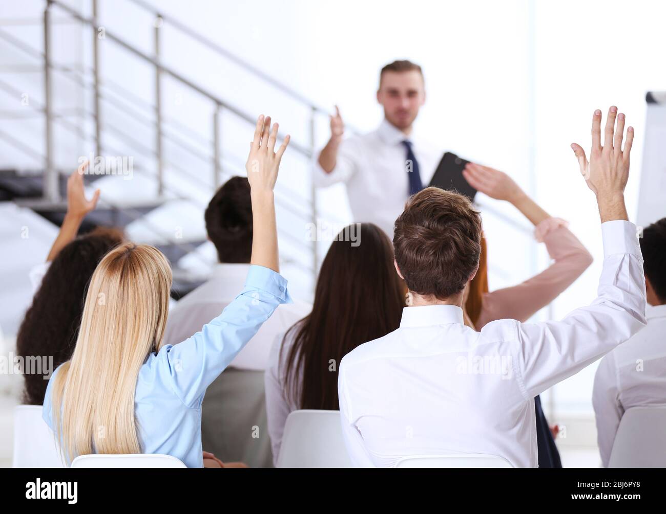Young colleagues raising hands at the business meeting in office Stock ...
