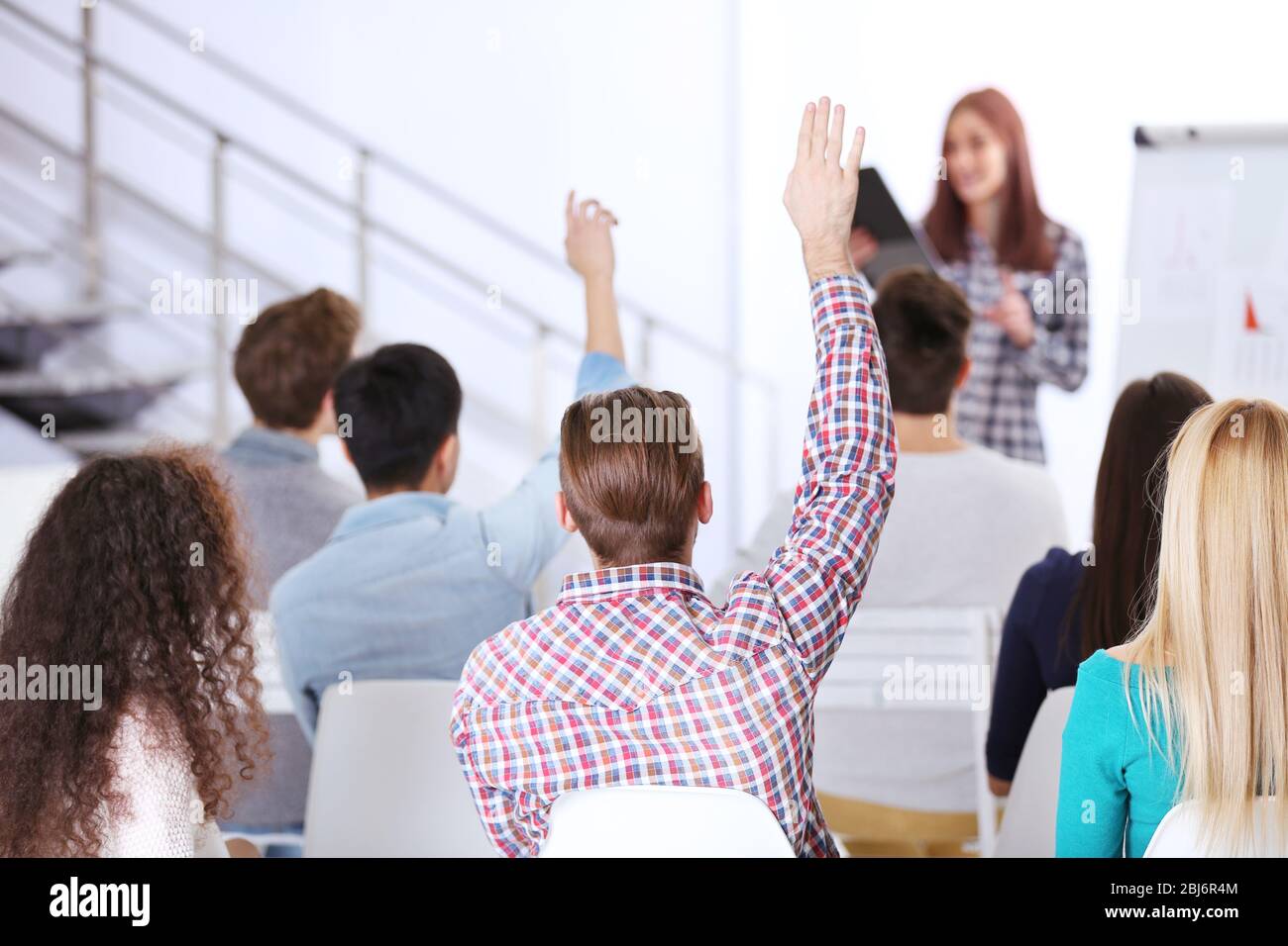 Young man with raised hand sitting back at the office meeting Stock ...