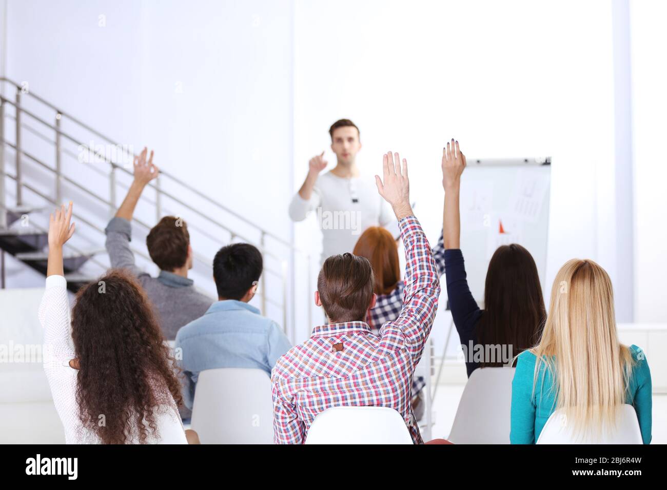 Young colleagues raising hands at the business meeting in office Stock ...