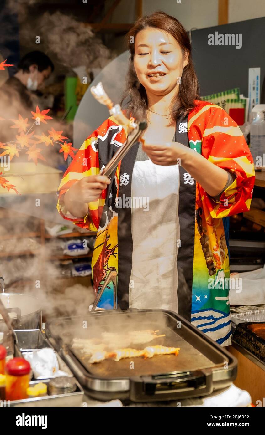 A seller at the Nishiki food market in Kyoto Japan offering food for ...