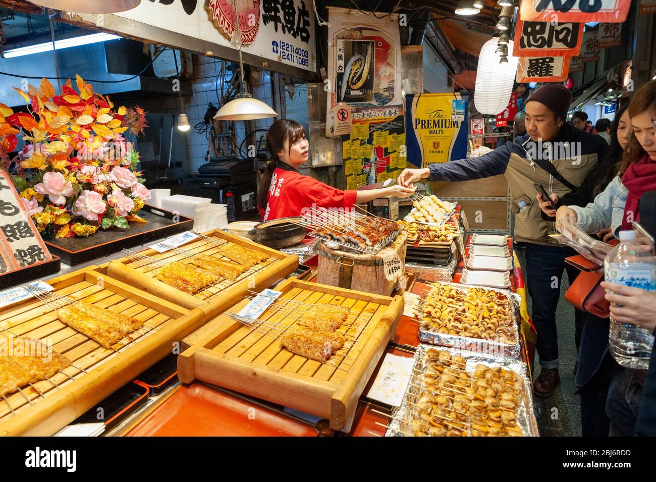 A seller at the Nishiki food market in Kyoto Japan offering food for ...
